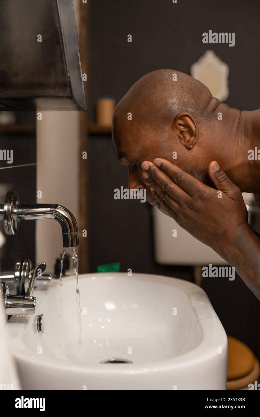Man washing face over bathroom sink Stock Photo - Alamy