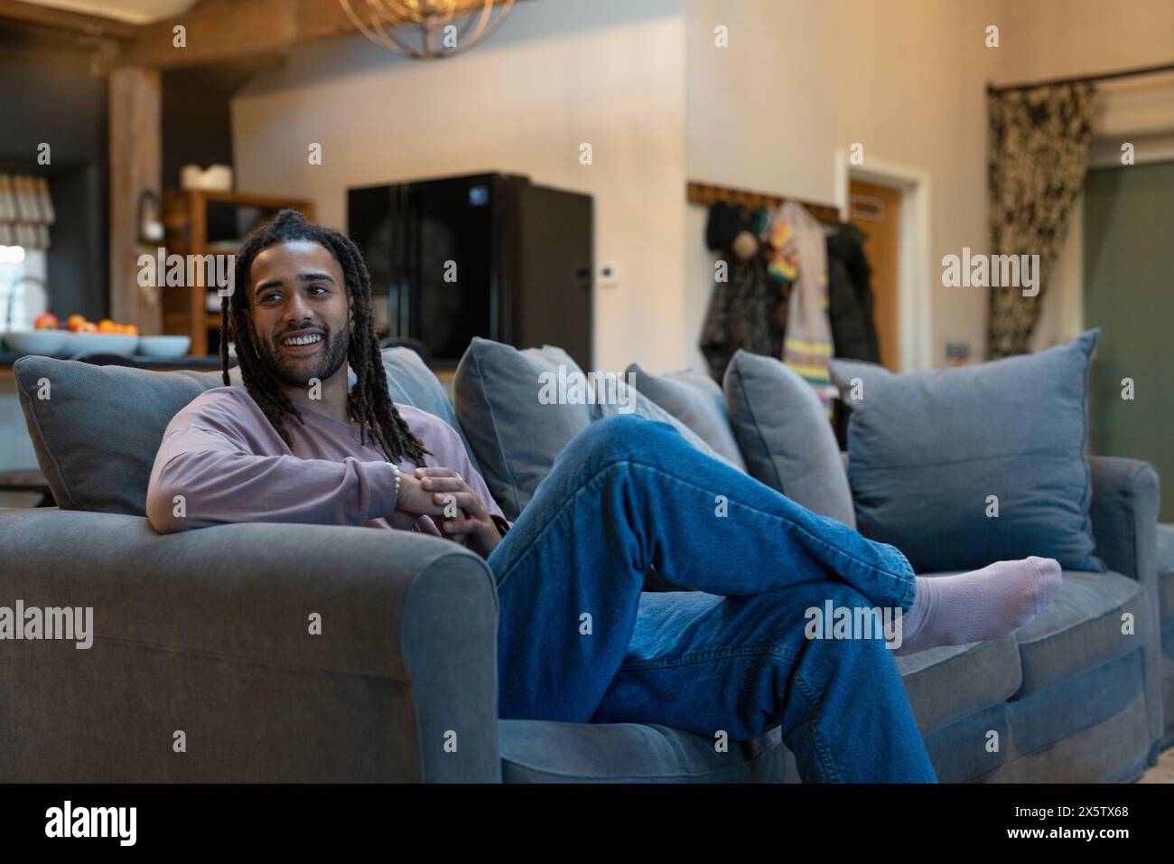 Handsome man with dreads relaxing on sofa Stock Photo - Alamy