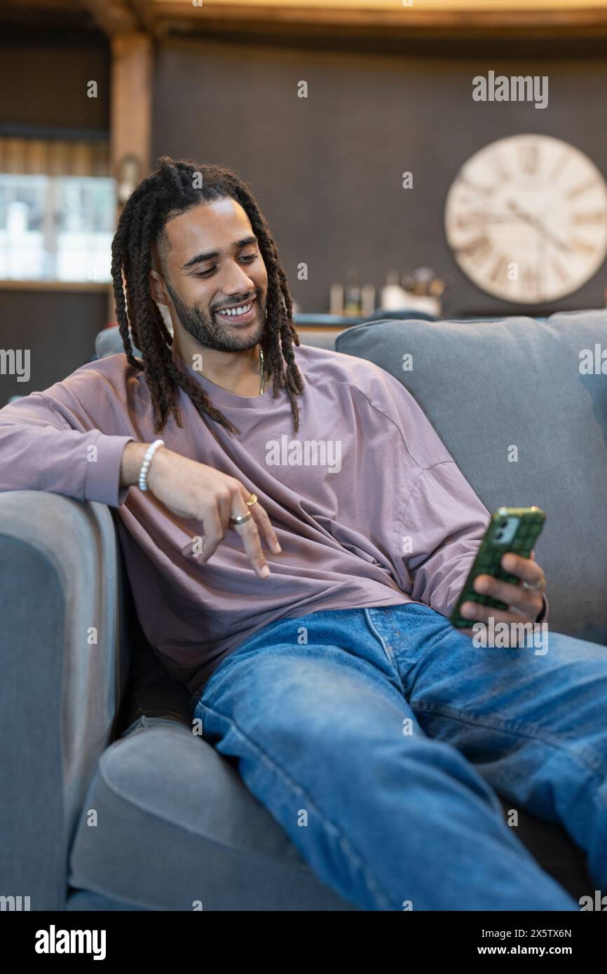 Man with dreads talking on video call while relaxing on sofa Stock ...