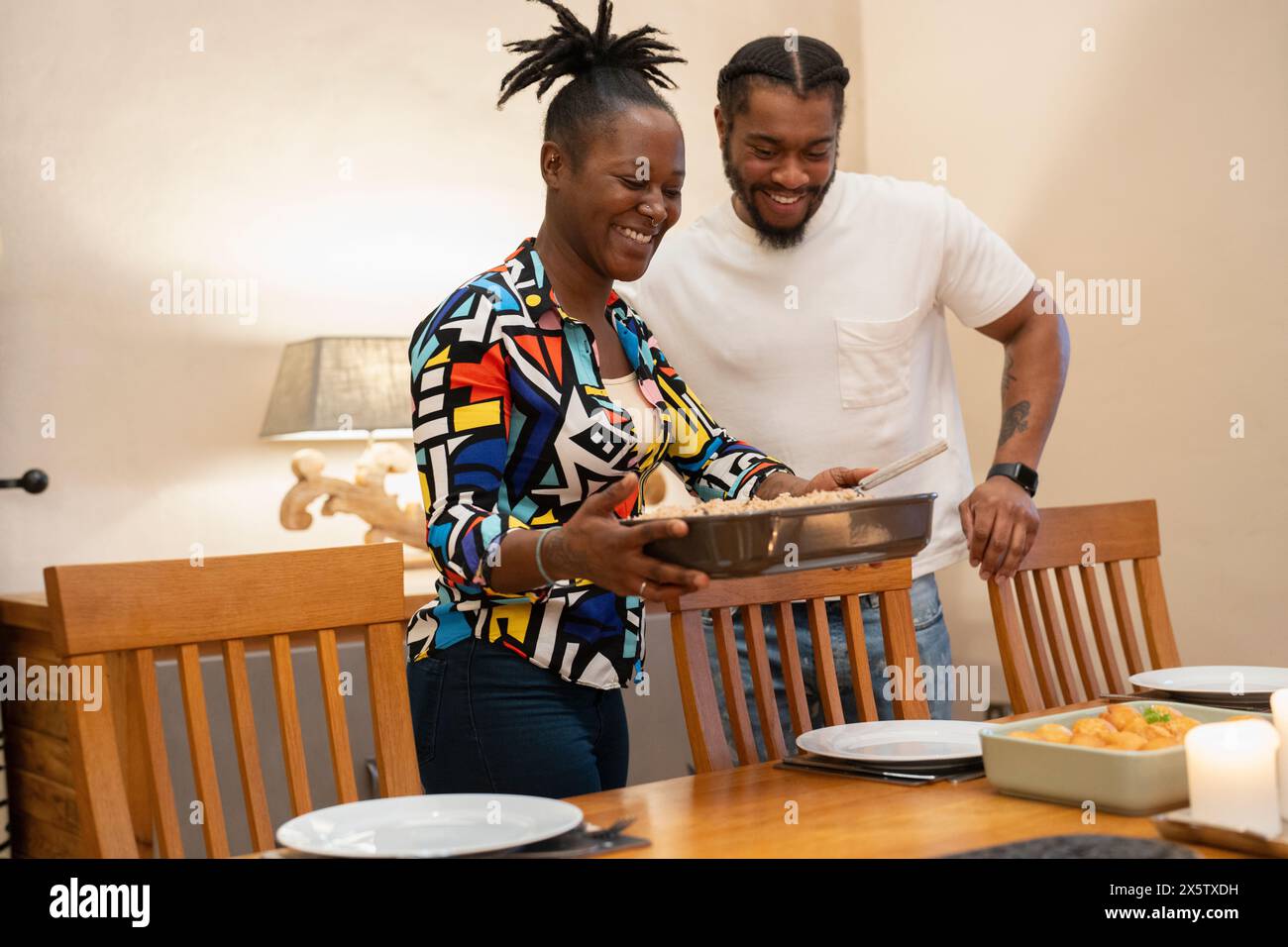 Smiling friends stand by table in dining room Stock Photo - Alamy