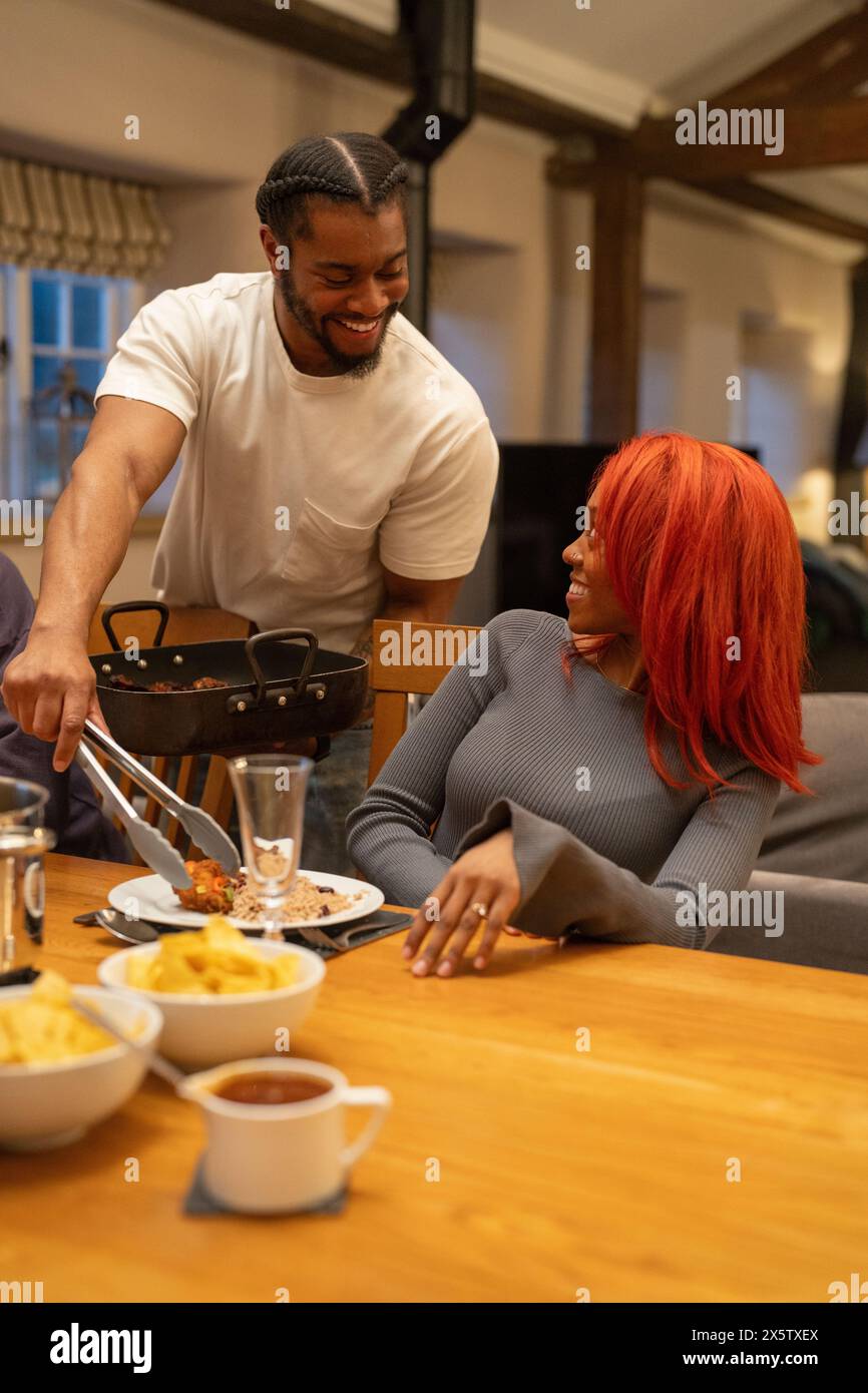 Man serves food to friend at dinner at home Stock Photo - Alamy