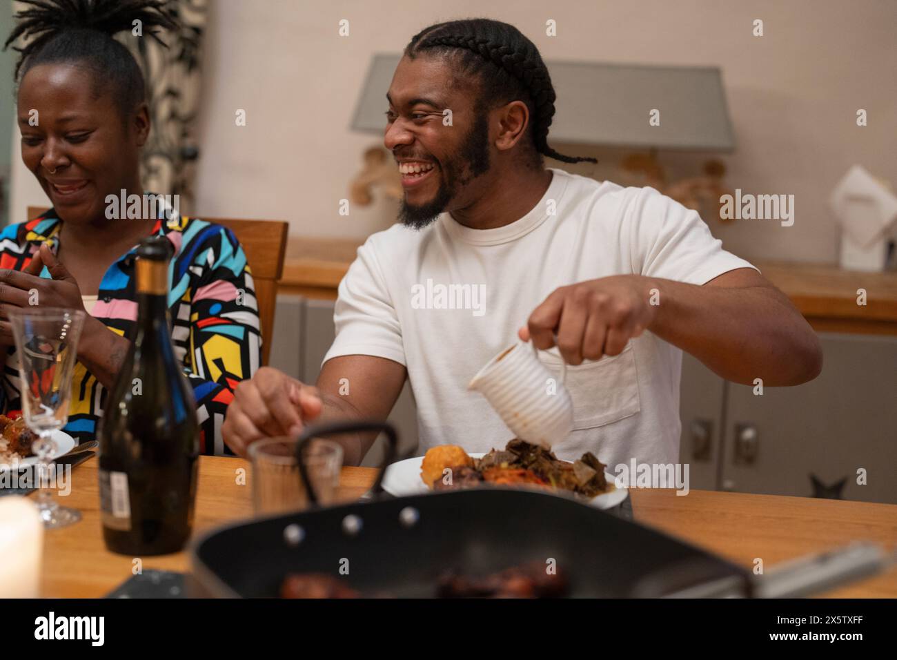 Smiling friends eating dinner together Stock Photo - Alamy