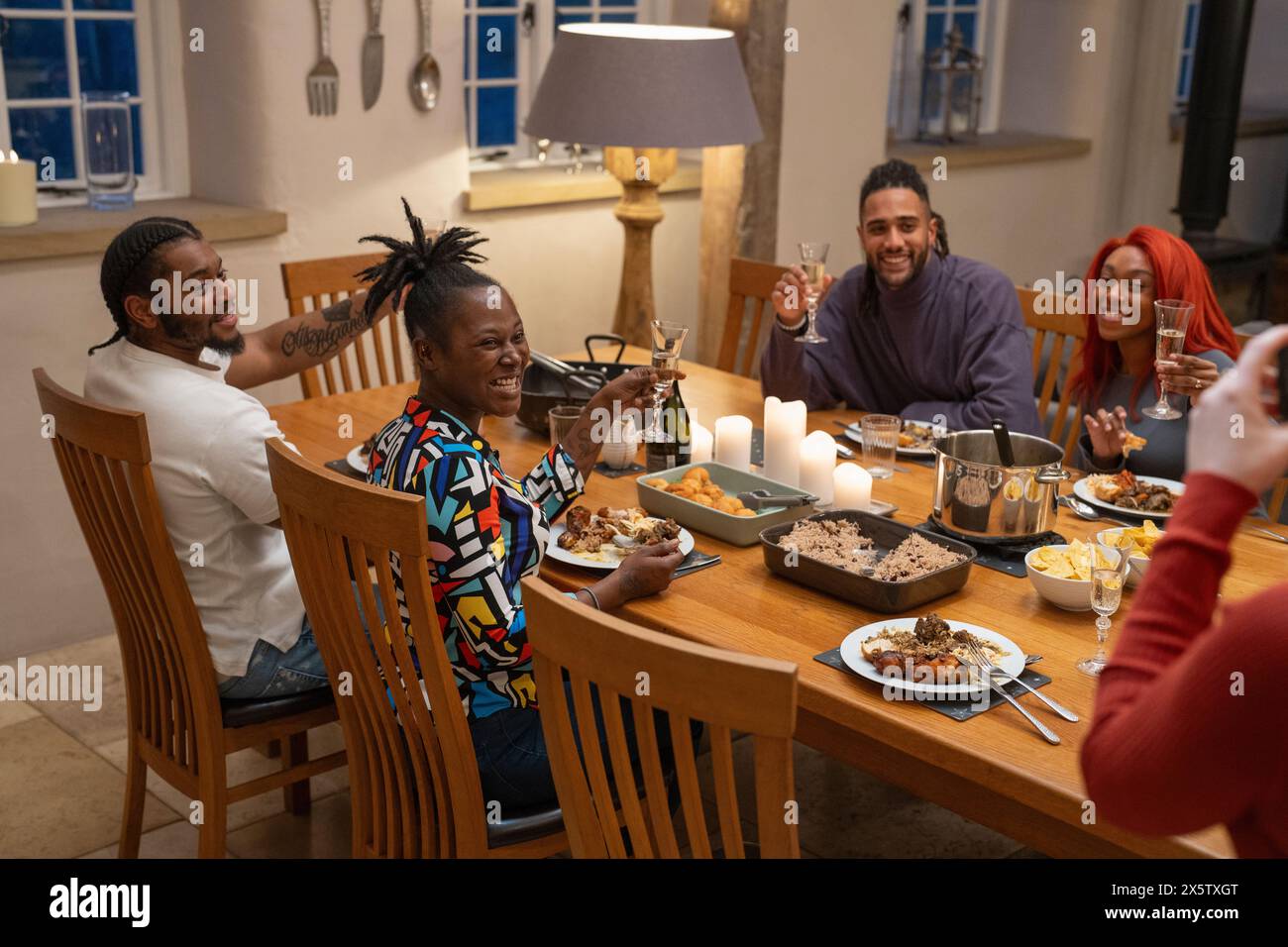 Friends pose for picture at dinner table, holding champagne flutes ...