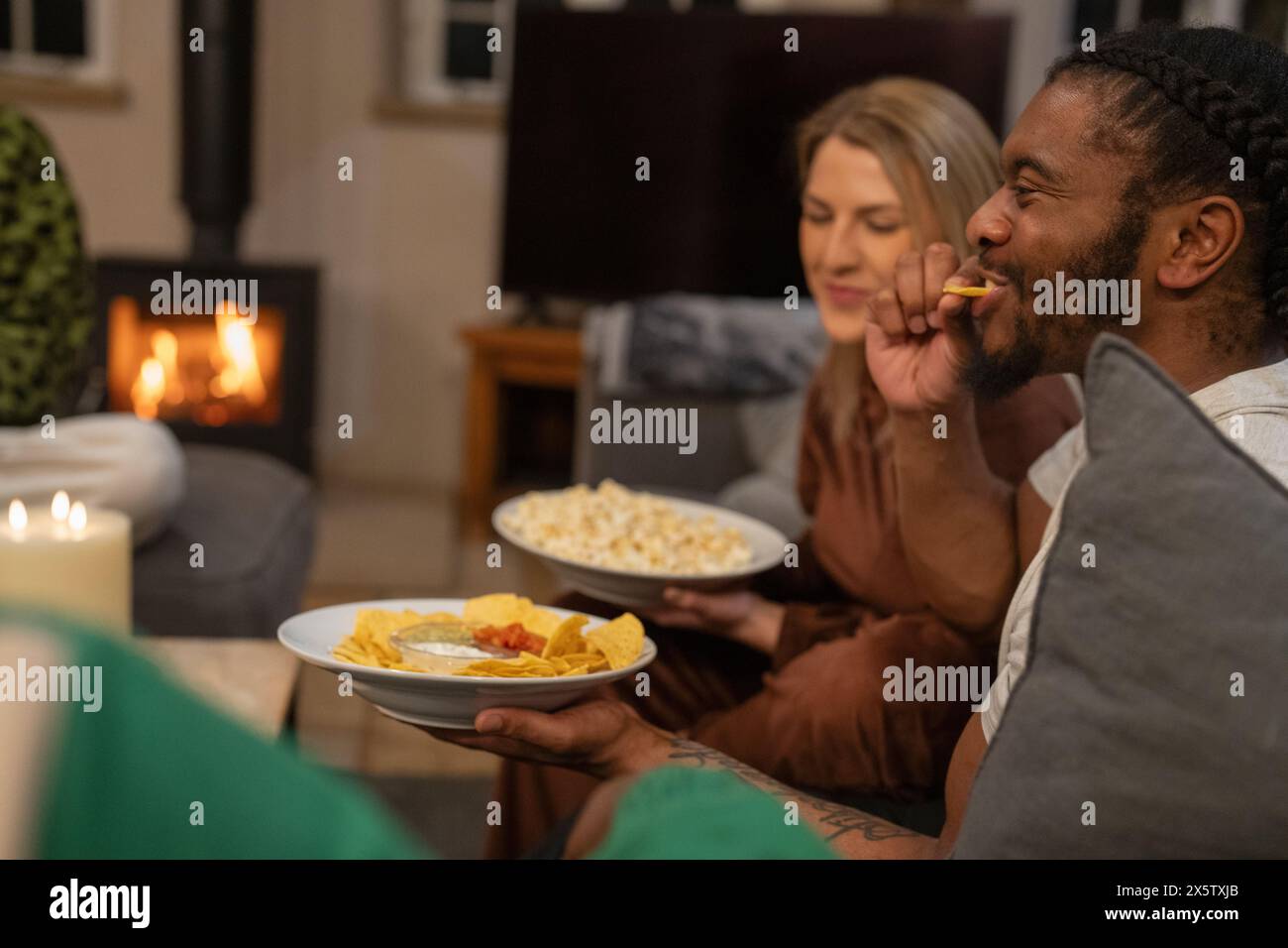 Smiling friends relaxing at home, eating tortilla chips Stock Photo - Alamy