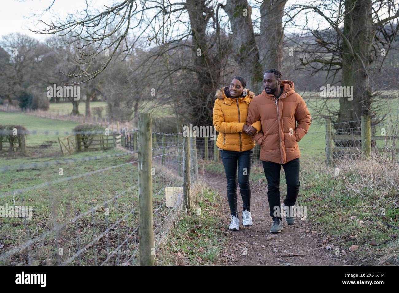 Couple in winter jackets walking in rural setting Stock Photo - Alamy