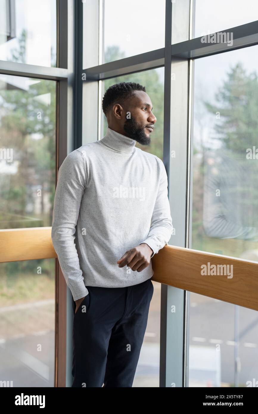 Young businessman looking through office window Stock Photo - Alamy