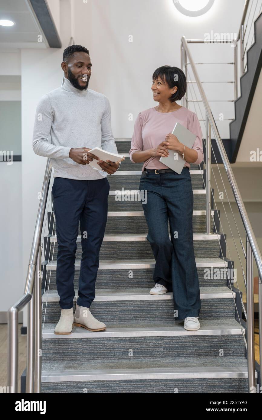 Business people walking down stairs and talking in office Stock Photo ...