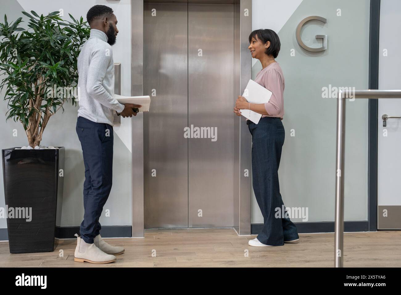Business people waiting for elevator in office Stock Photo - Alamy