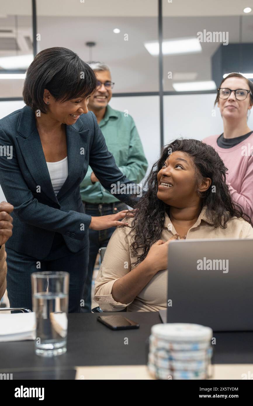 Business people congratulating colleague in office Stock Photo - Alamy