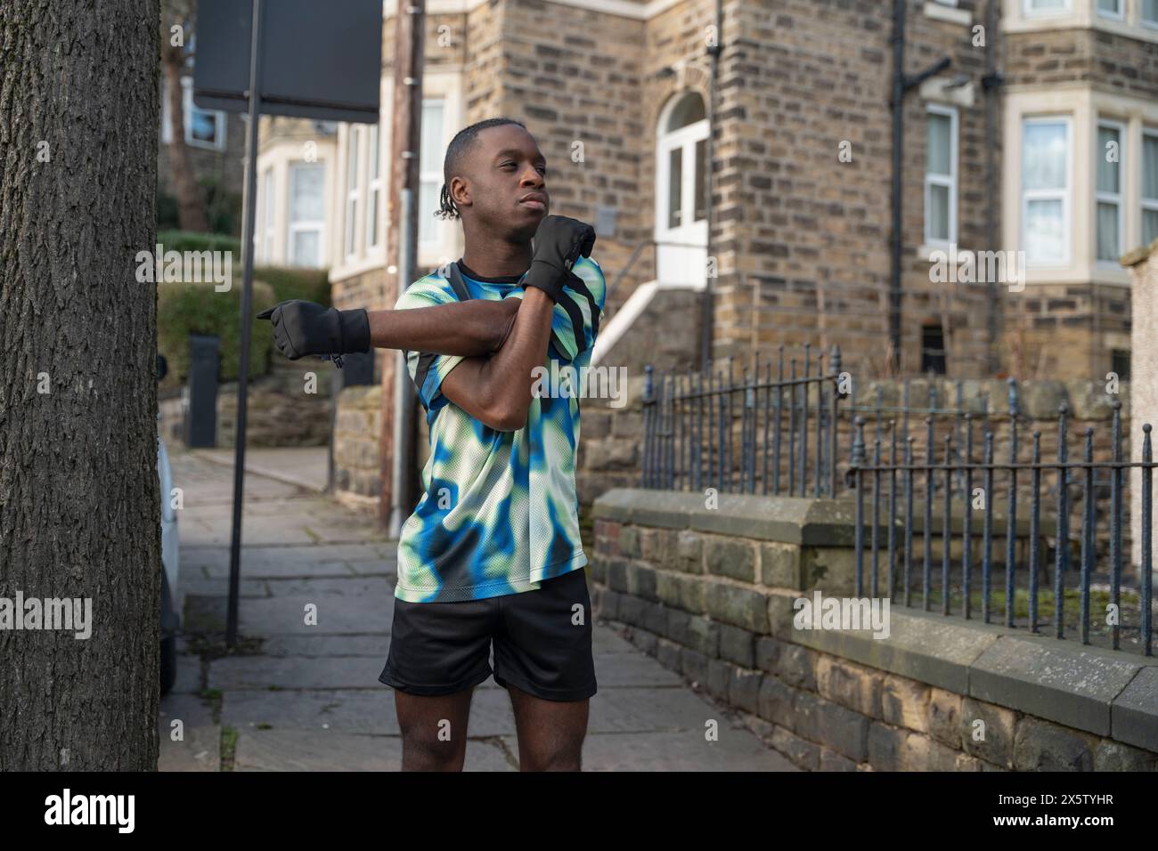 Athlete stretching arm on sidewalk Stock Photo - Alamy