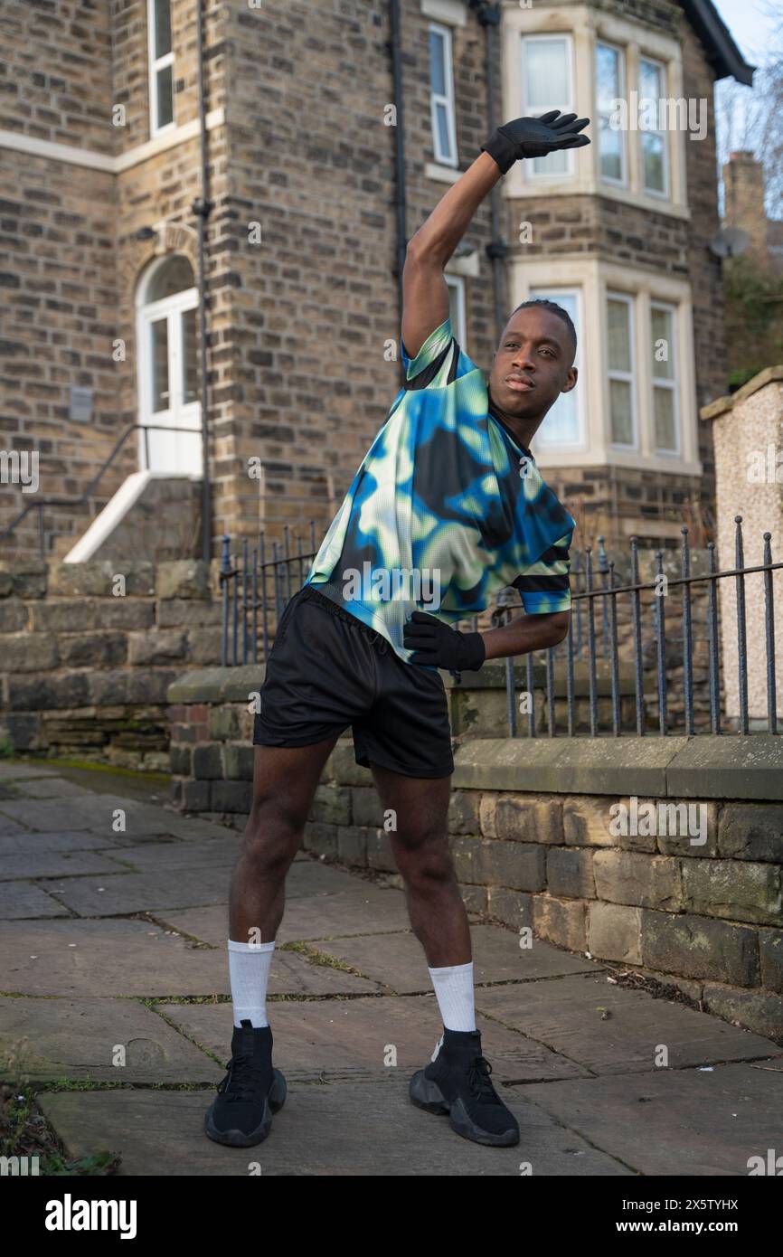 Athlete stretching arm on sidewalk Stock Photo - Alamy