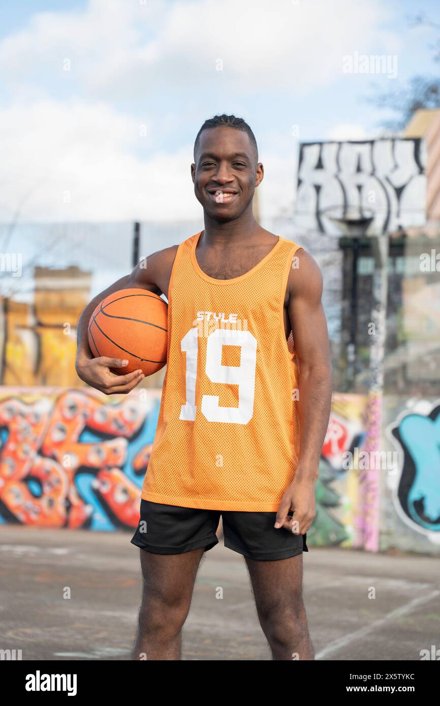 Portrait of smiling basketball player holding ball Stock Photo - Alamy