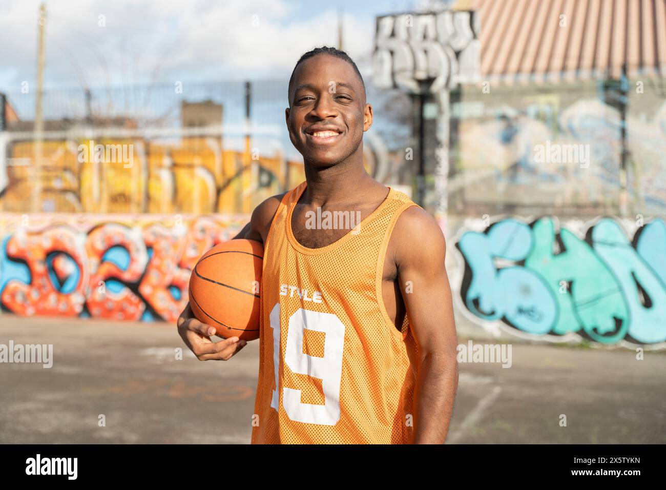 Portrait of smiling basketball player holding ball Stock Photo - Alamy