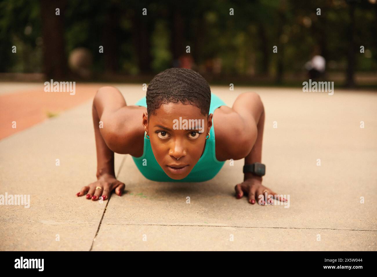 Athlete woman in sports clothing doing push-ups in park Stock Photo - Alamy
