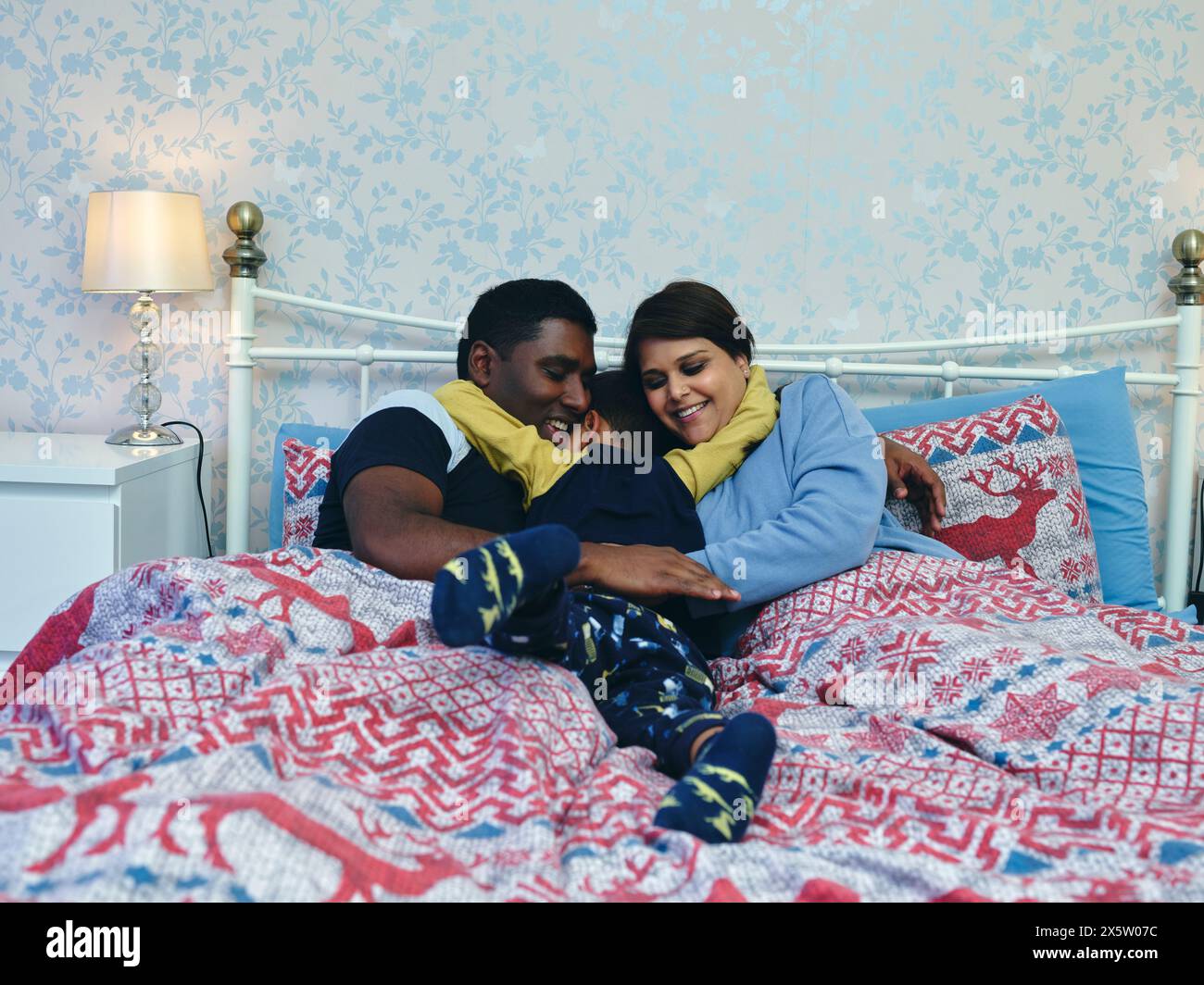 Boy hugging parents in bed Stock Photo - Alamy