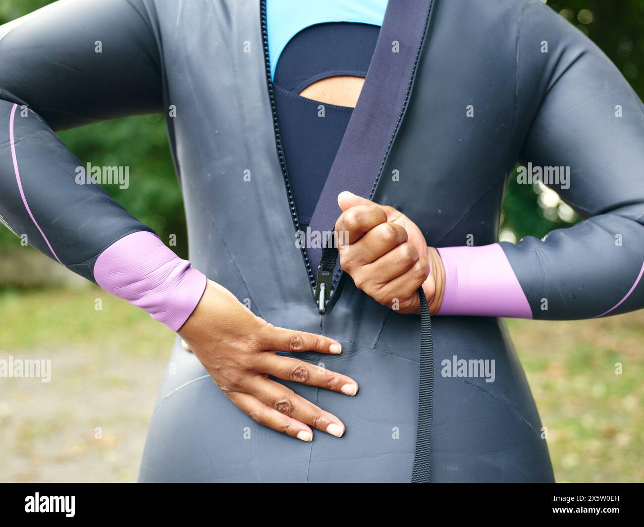 Rear view of woman putting on wetsuit Stock Photo - Alamy