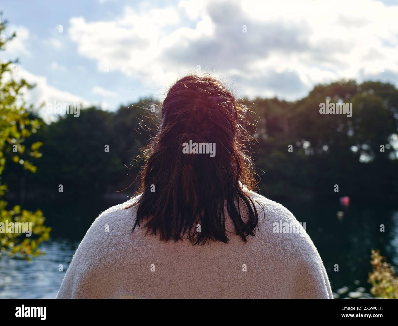 Rear view of woman wrapped in towel looking at river Stock Photo - Alamy