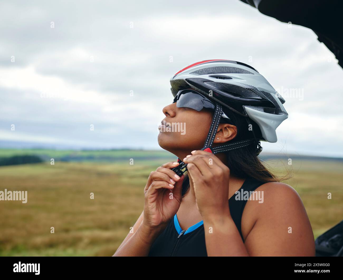 Woman putting on bicycle helmet Stock Photo - Alamy