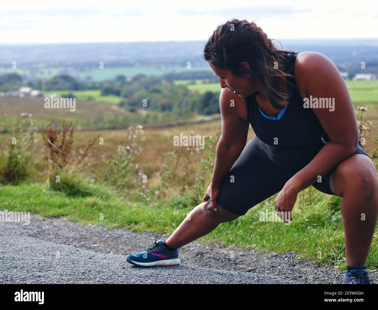 Female runner stretching on roadside Stock Photo - Alamy