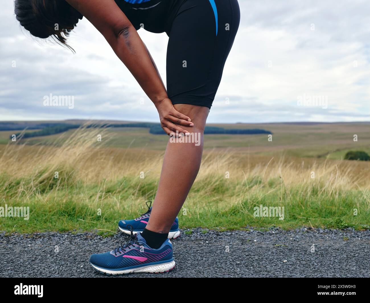 Tired female runner resting on roadside Stock Photo - Alamy