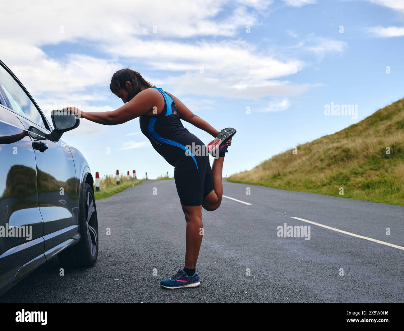 Female runner stretching by car Stock Photo - Alamy