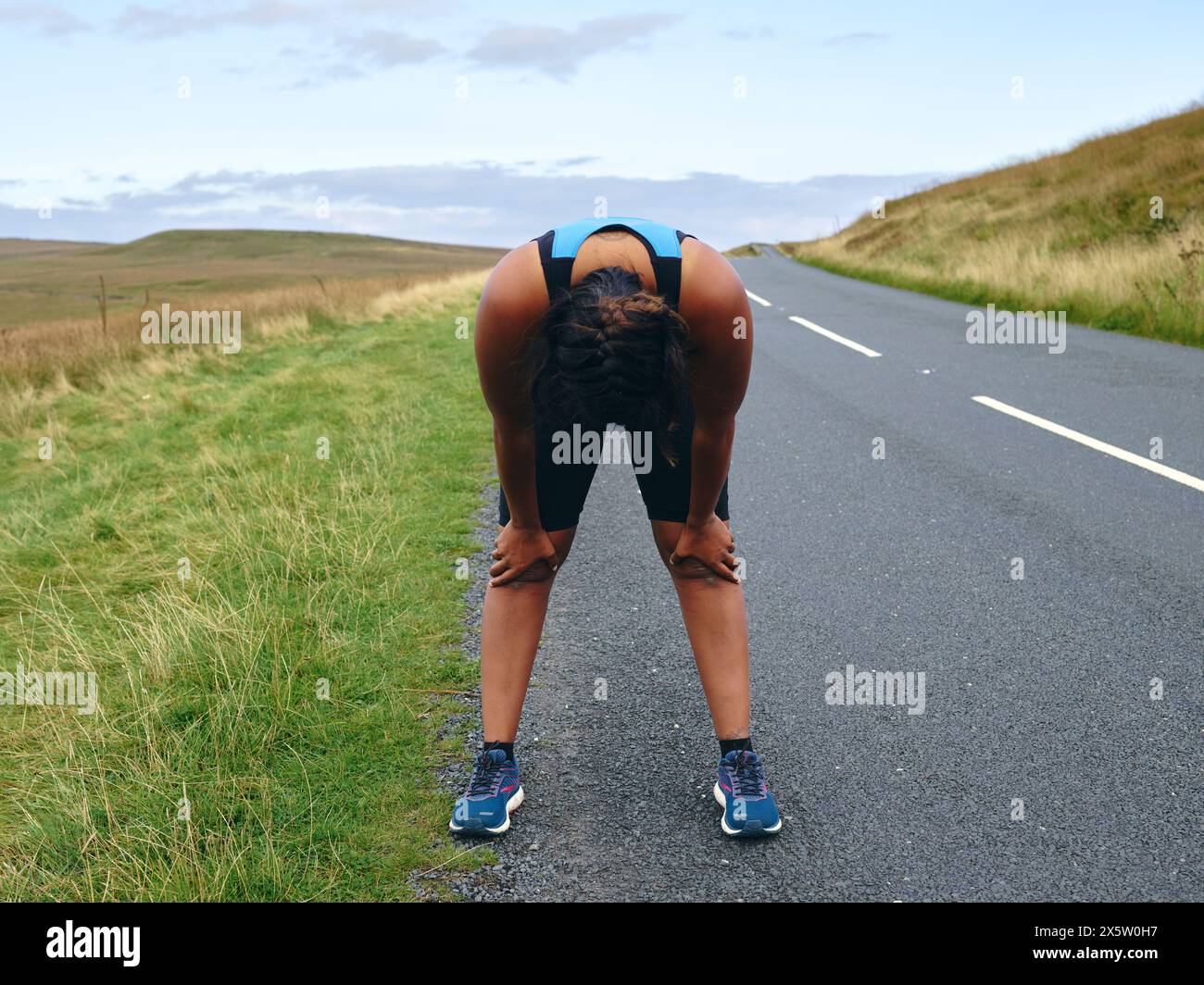 Tired female runner resting on roadside Stock Photo - Alamy