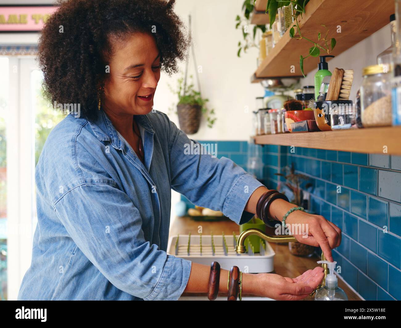 Woman washing hands in kitchen Stock Photo - Alamy