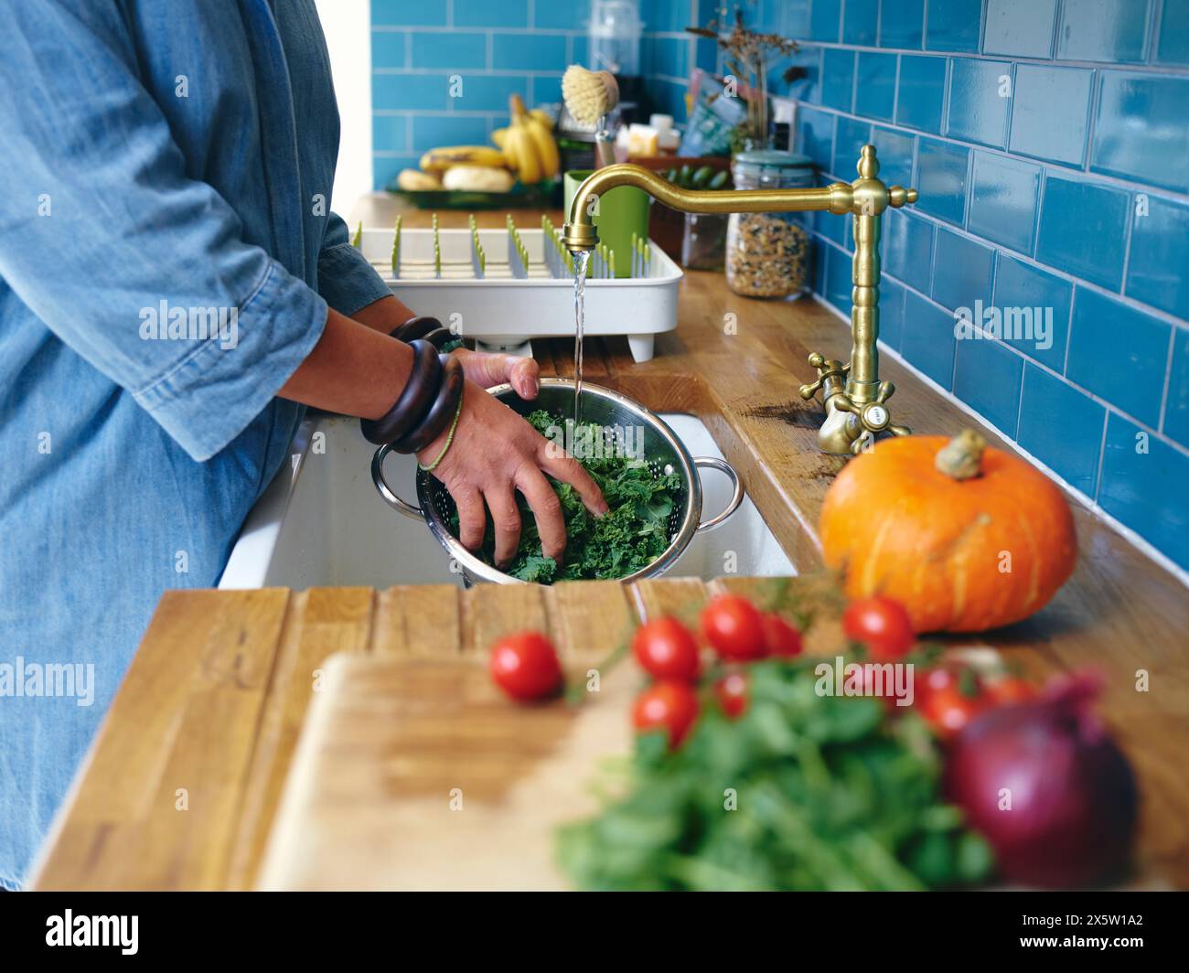 Woman washing vegetables in kitchen sink Stock Photo - Alamy