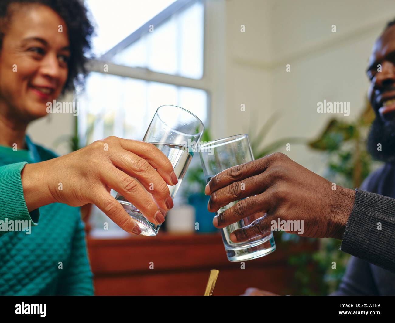 Couple raising toast with glasses of water Stock Photo - Alamy