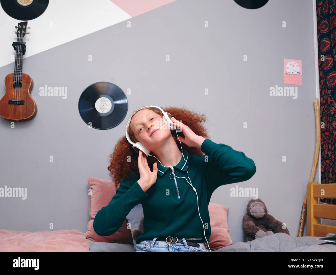 Girl wearing headphones, sitting on bed Stock Photo - Alamy