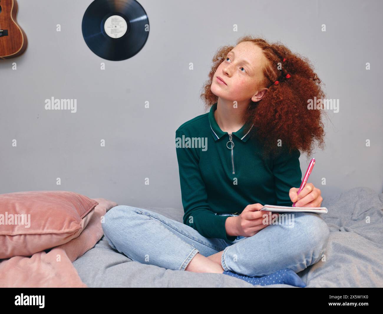 Girl sitting on bed and writing in notepad Stock Photo - Alamy
