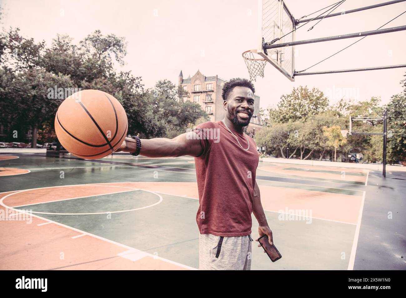 USA, Pennsylvania, Philadelphia, Smiling man with ball at basketball ...