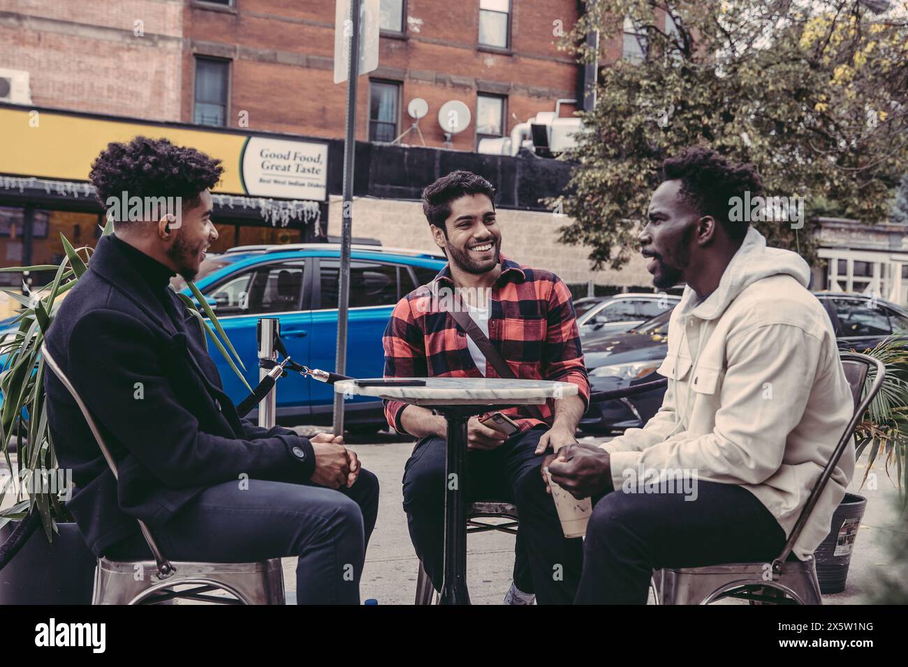 USA, Pennsylvania, Philadelphia, Three male friends talking at sidewalk ...