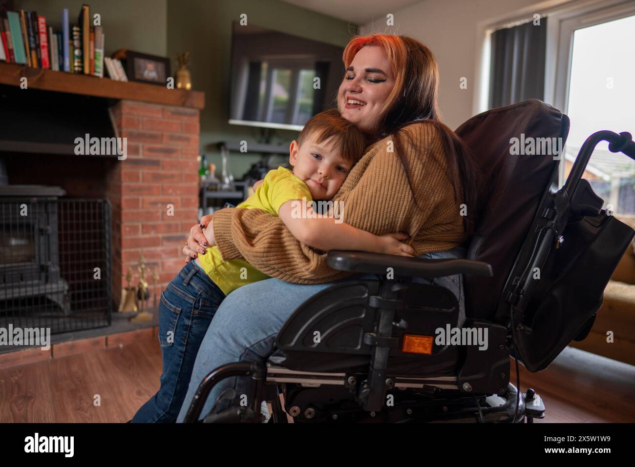 Woman on wheelchair hugging son Stock Photo - Alamy