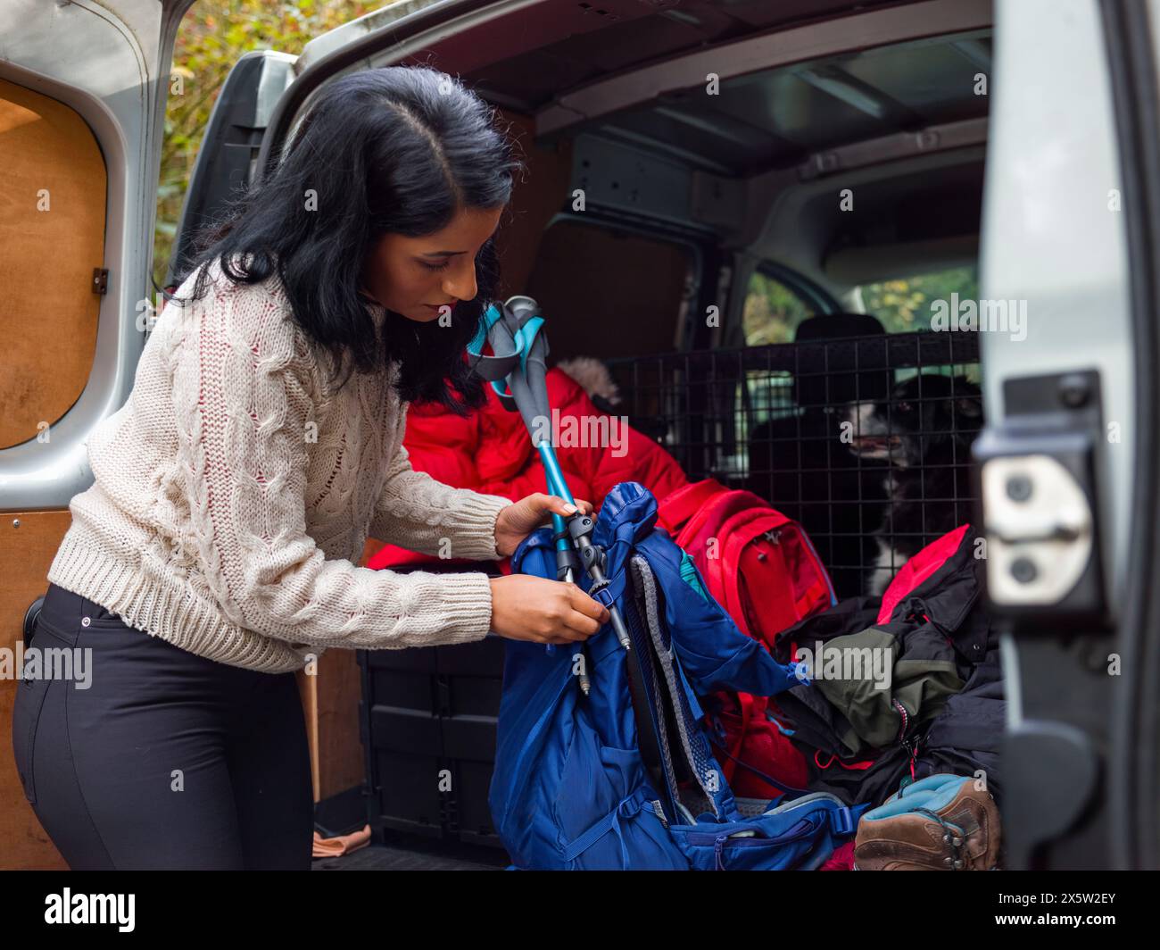 Woman taking hiking equipment from back of van Stock Photo - Alamy