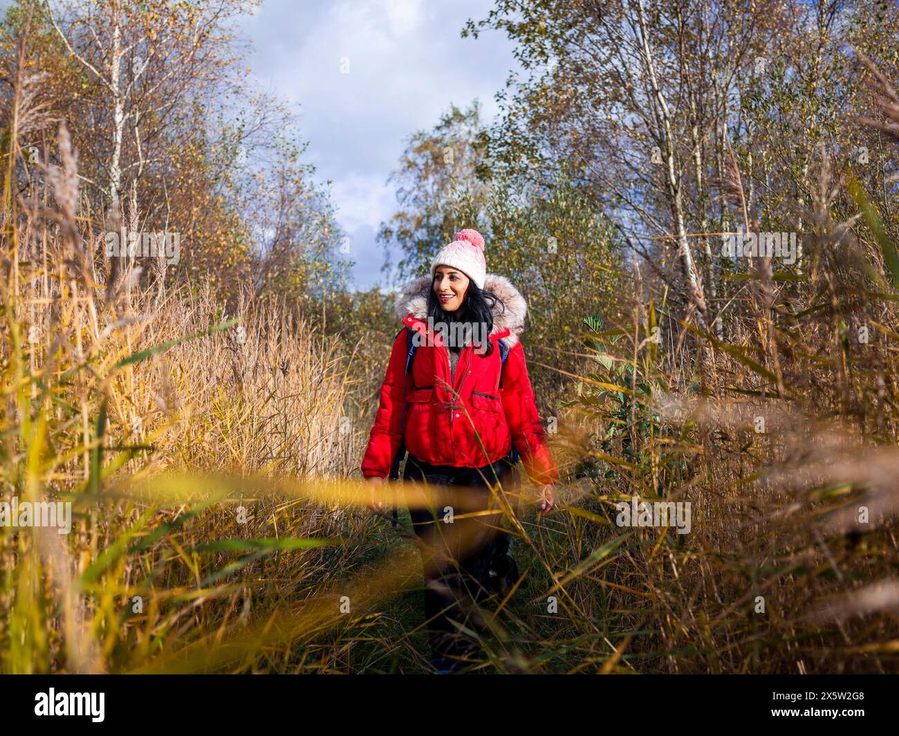 Female hiker walking through tall grass Stock Photo - Alamy
