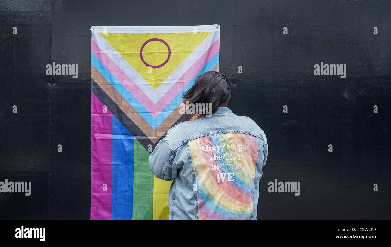 Mature woman wearing denim jacket in front of pride flag Stock Photo ...