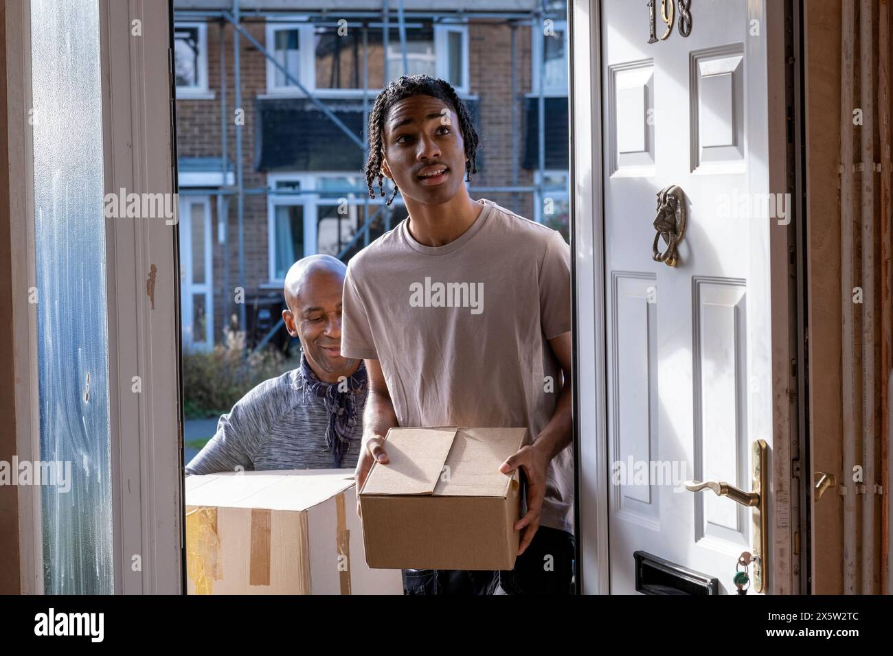 Father and son entering house with cardboard boxes Stock Photo - Alamy