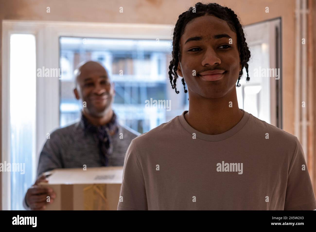 Father and son entering house with cardboard boxes Stock Photo - Alamy