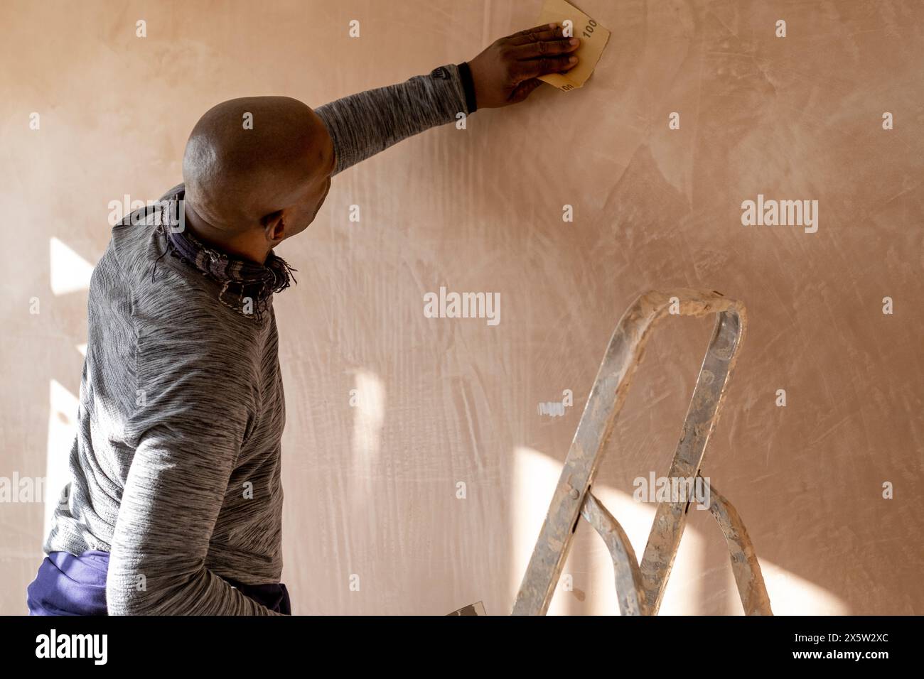 Man sanding wall in house Stock Photo - Alamy