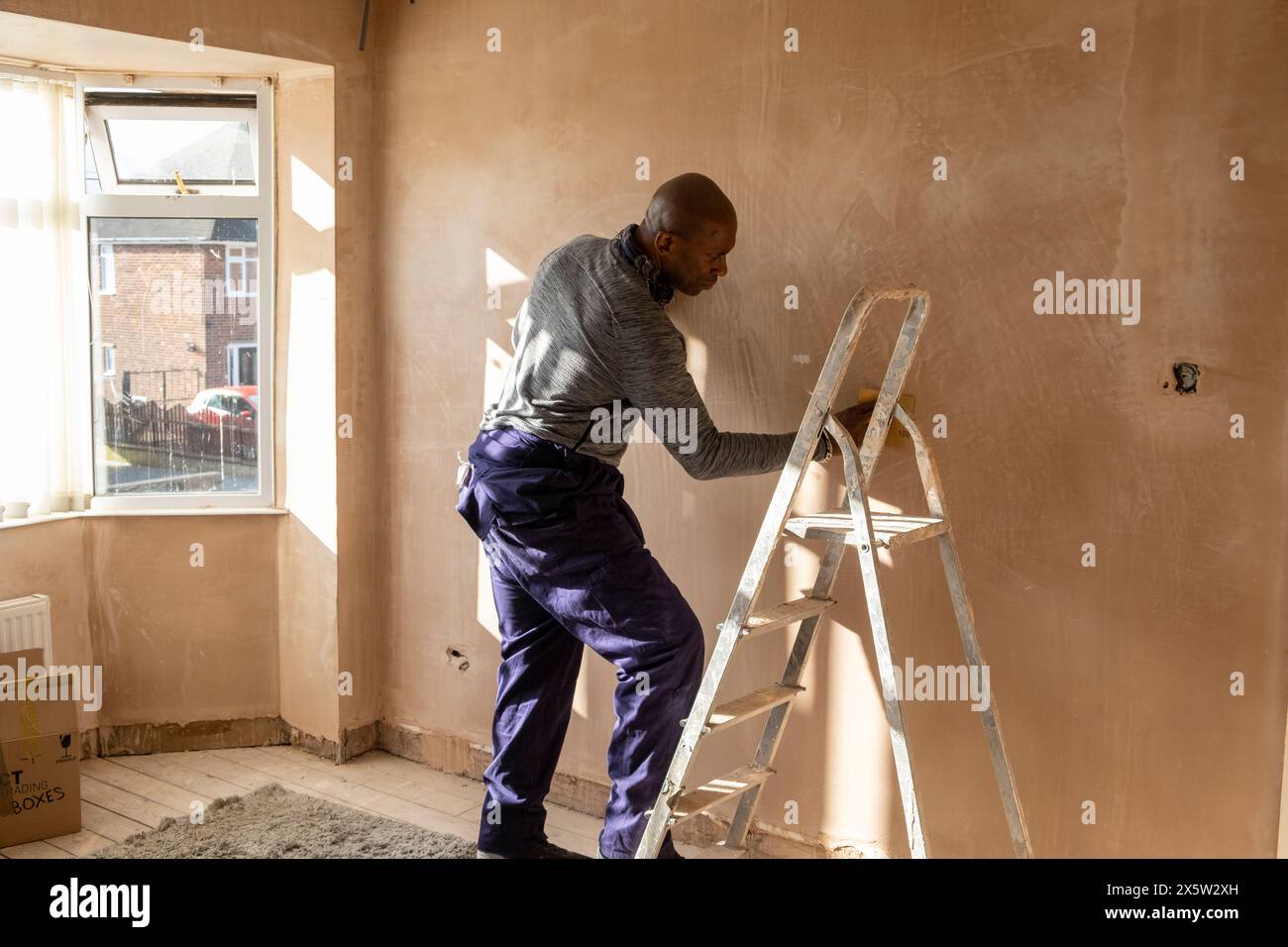 Man sanding wall in house Stock Photo - Alamy