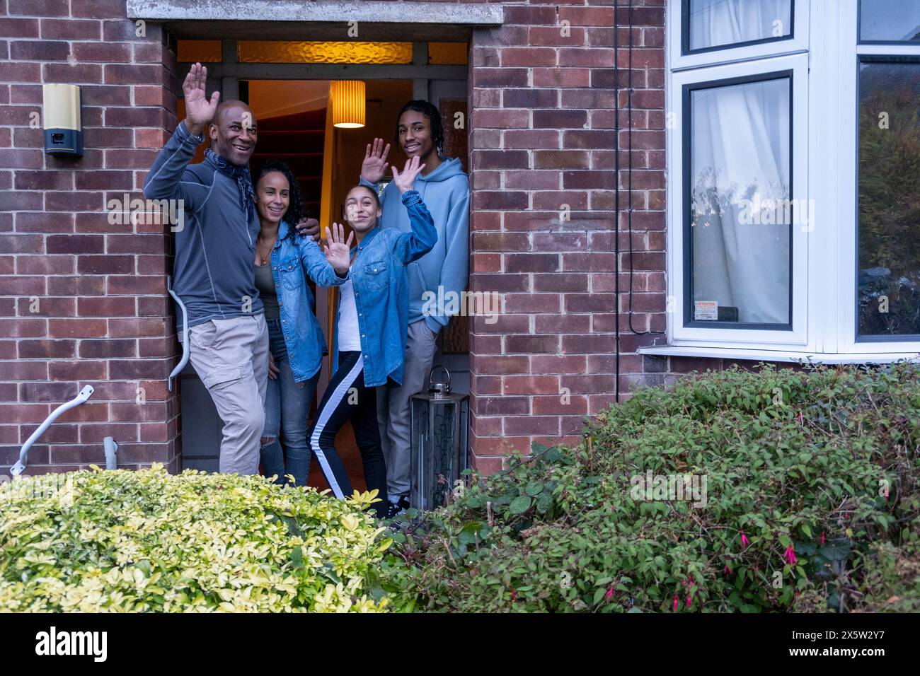 Family with daughter and son waving in front of new house Stock Photo ...