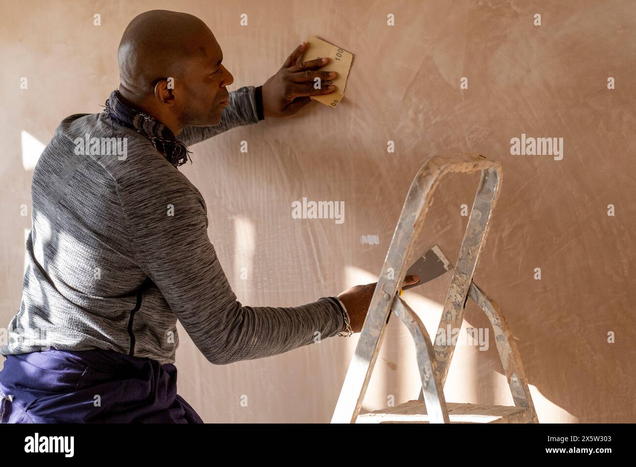 Man sanding wall in house Stock Photo - Alamy