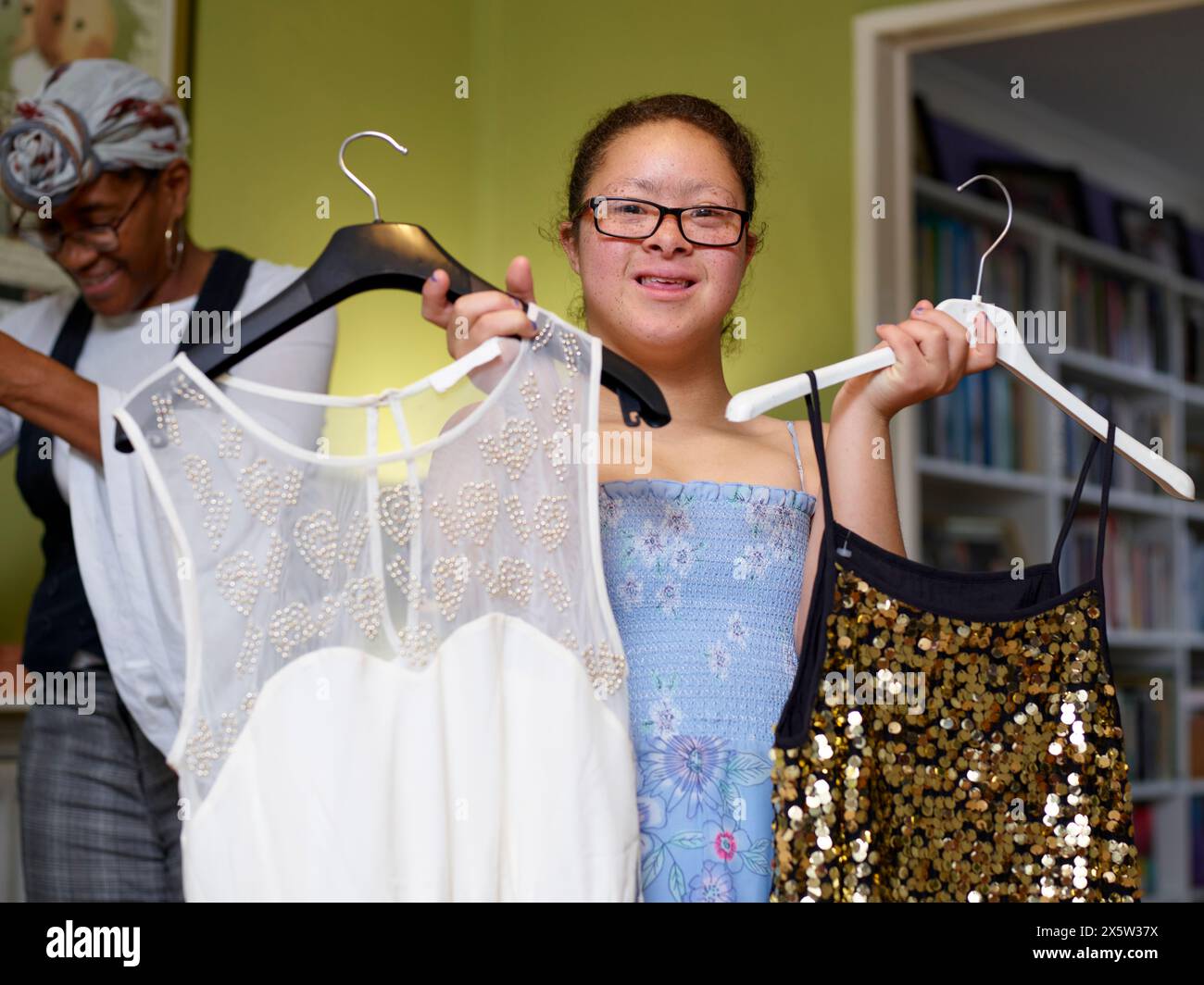 Girl with Down Syndrome holding coathangers with dresses Stock Photo ...