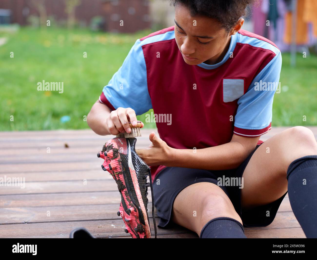 Female soccer player cleaning shoe on patio Stock Photo - Alamy