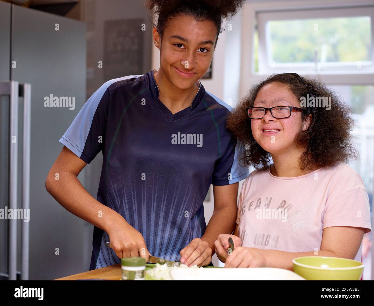 Portrait of sisters preparing food in kitchen Stock Photo - Alamy