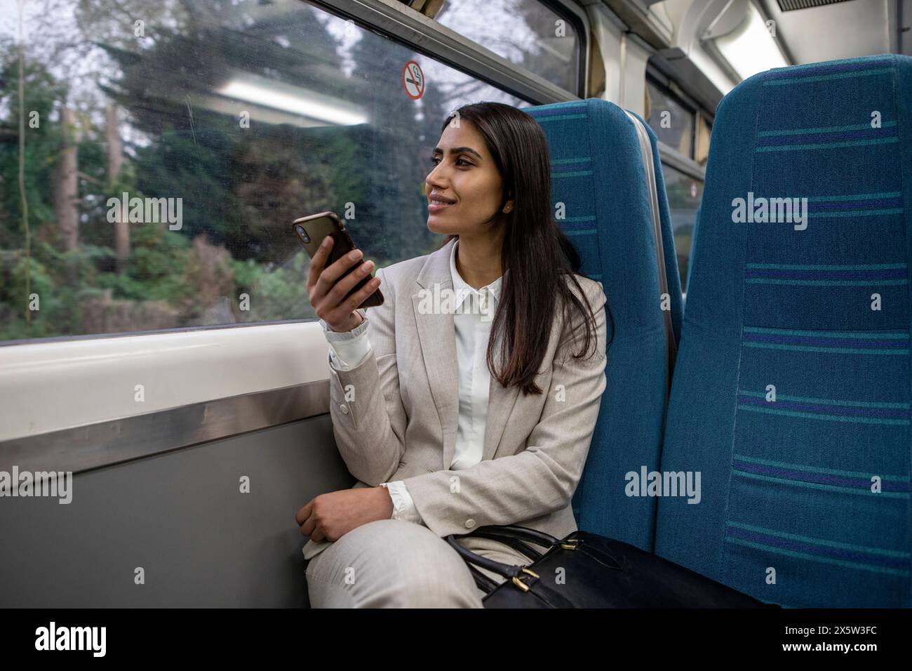Smiling businesswoman using smart phone in commuter train Stock Photo ...