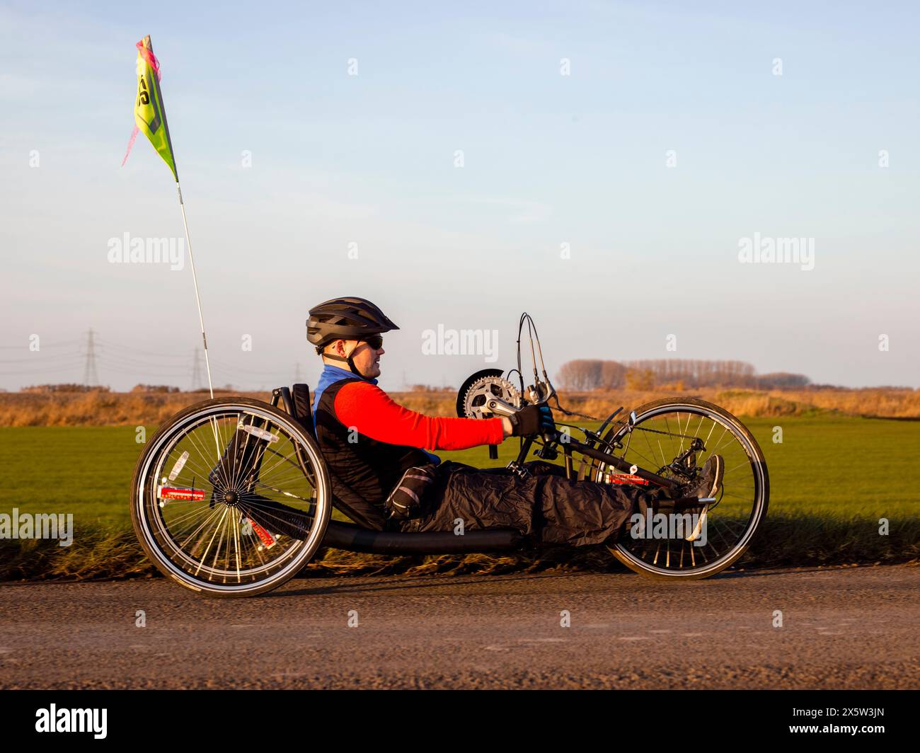 Disabled man riding handcycle on country road Stock Photo - Alamy