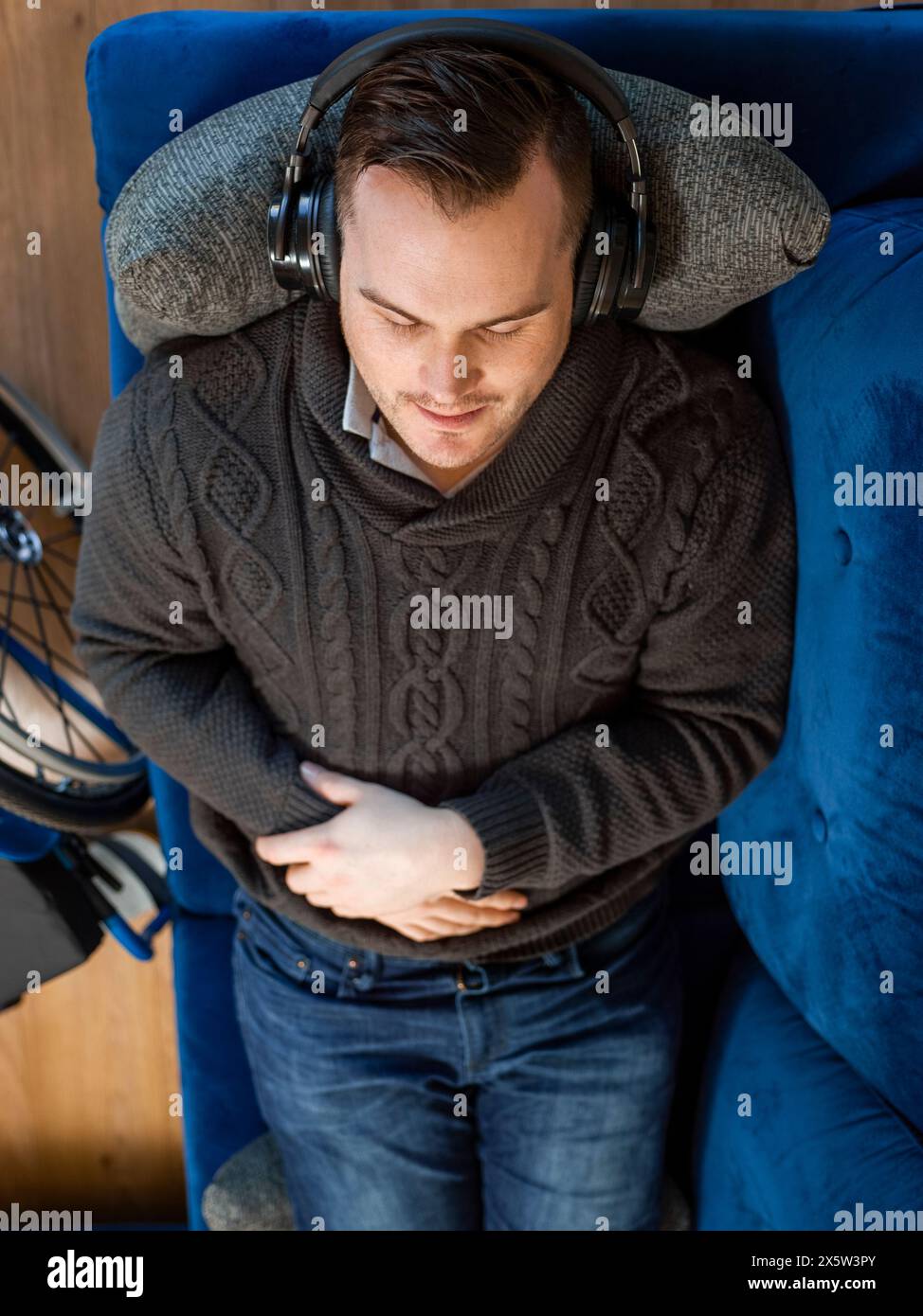 Overhead view of man with headphones on sofa next to wheelchair Stock ...