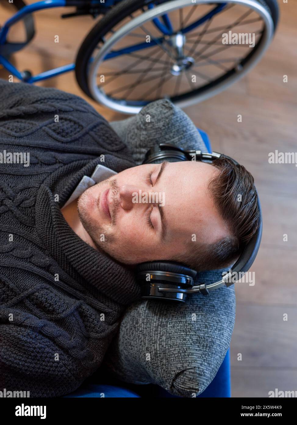 Overhead view of man with headphones on sofa next to wheelchair Stock ...